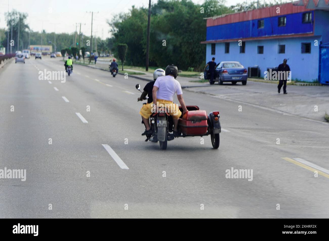 Motorbike with sidecar driving on a road, several vehicles and people ...
