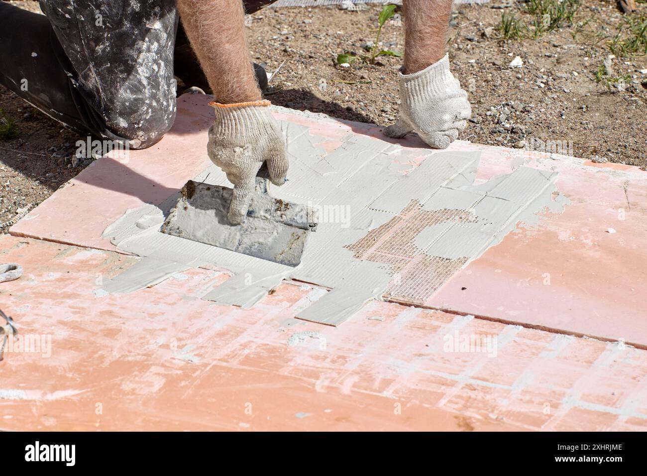 Construction worker uses steel trowel to apply adhesive cement mortar ...