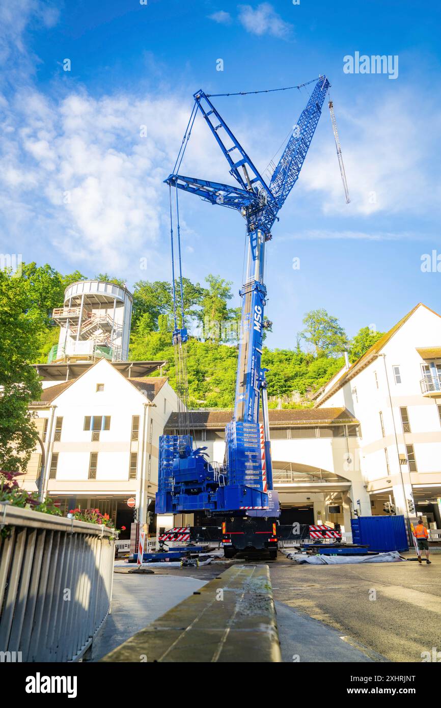 A blue construction crane in an urban area with houses and lots of ...