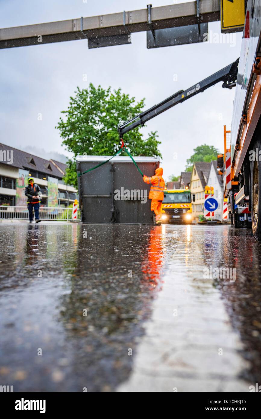 Construction worker moving a traffic light bridge with a crane on a wet ...