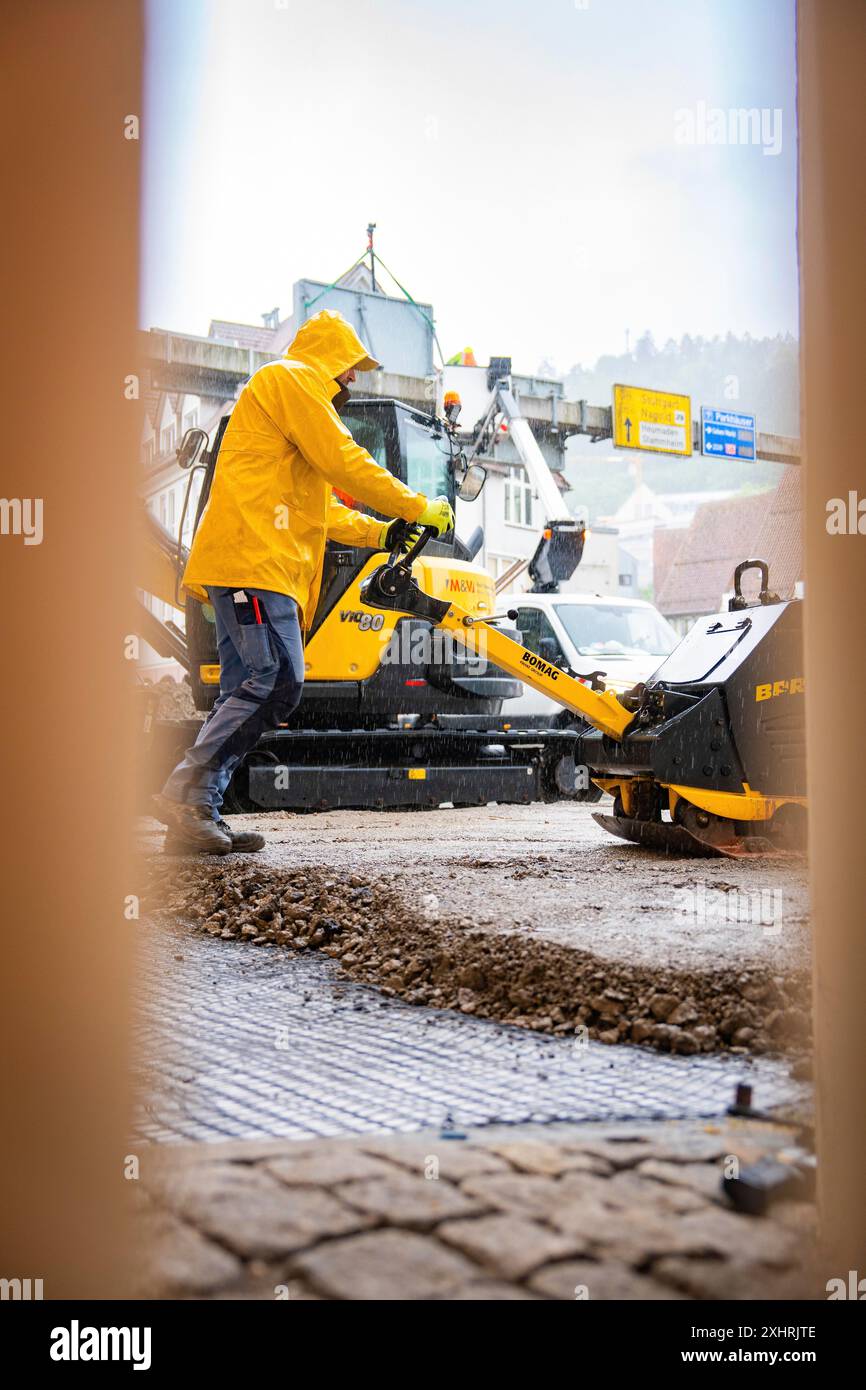 Construction worker in yellow rain jacket operating construction ...