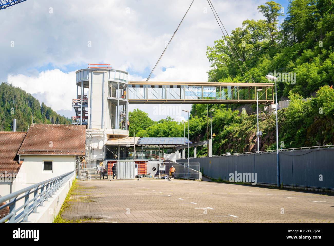 A lifted bridge over a building complex, held by a crane, in sunny ...