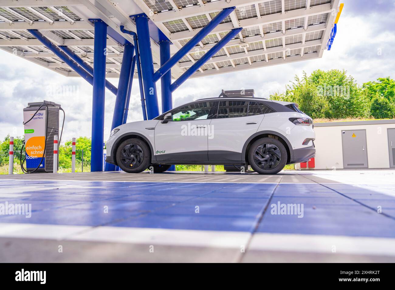 Electric vehicle being charged at a modern charging station under a ...