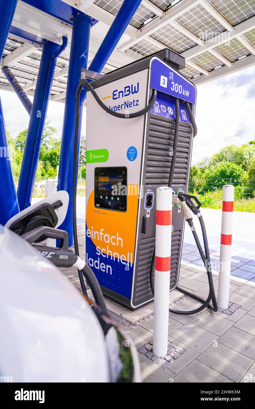 Close-up of an EnBW charging station, with an electric car next to it ...