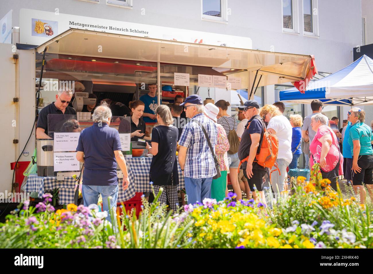 Crowded market stall with people queuing to buy food while flowers ...