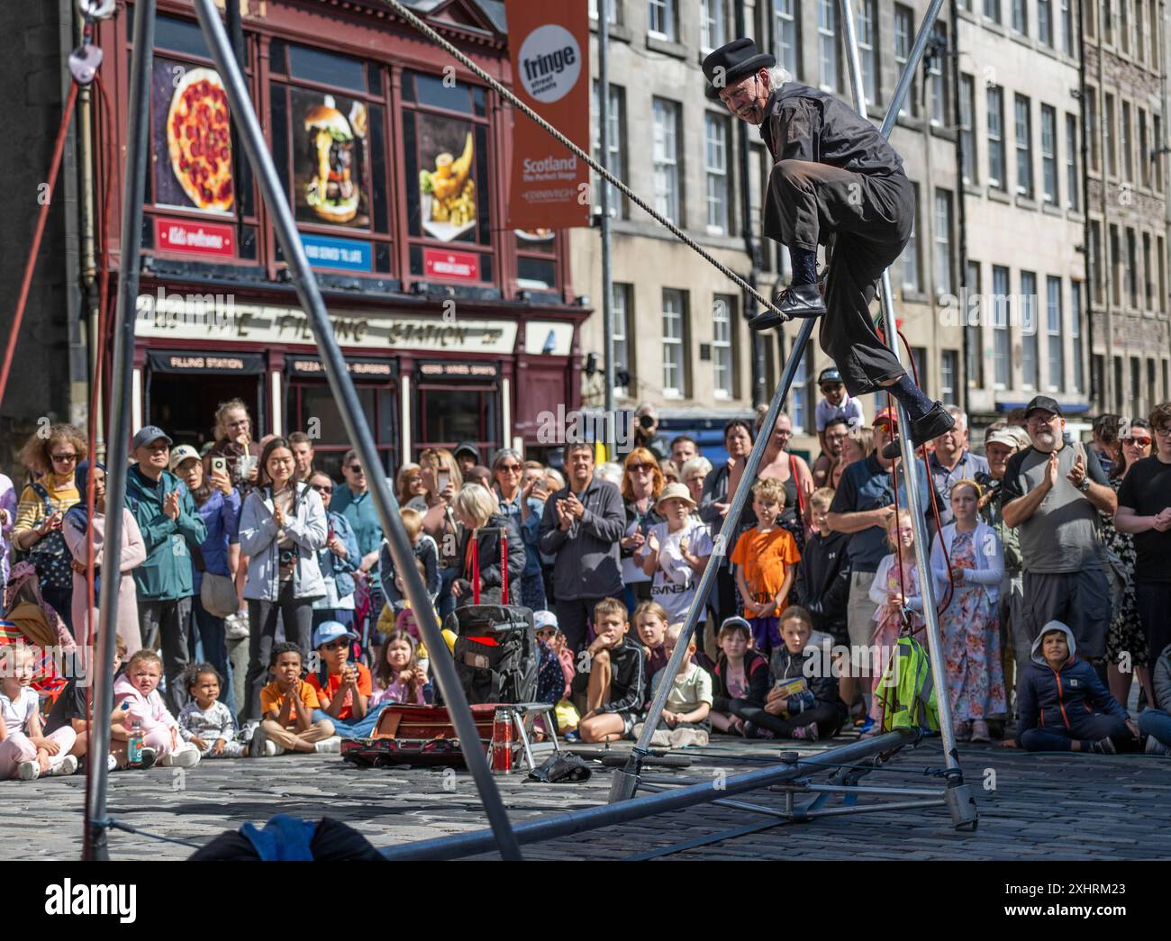 Street performers and spectators at a high-wire acrobatics performance ...