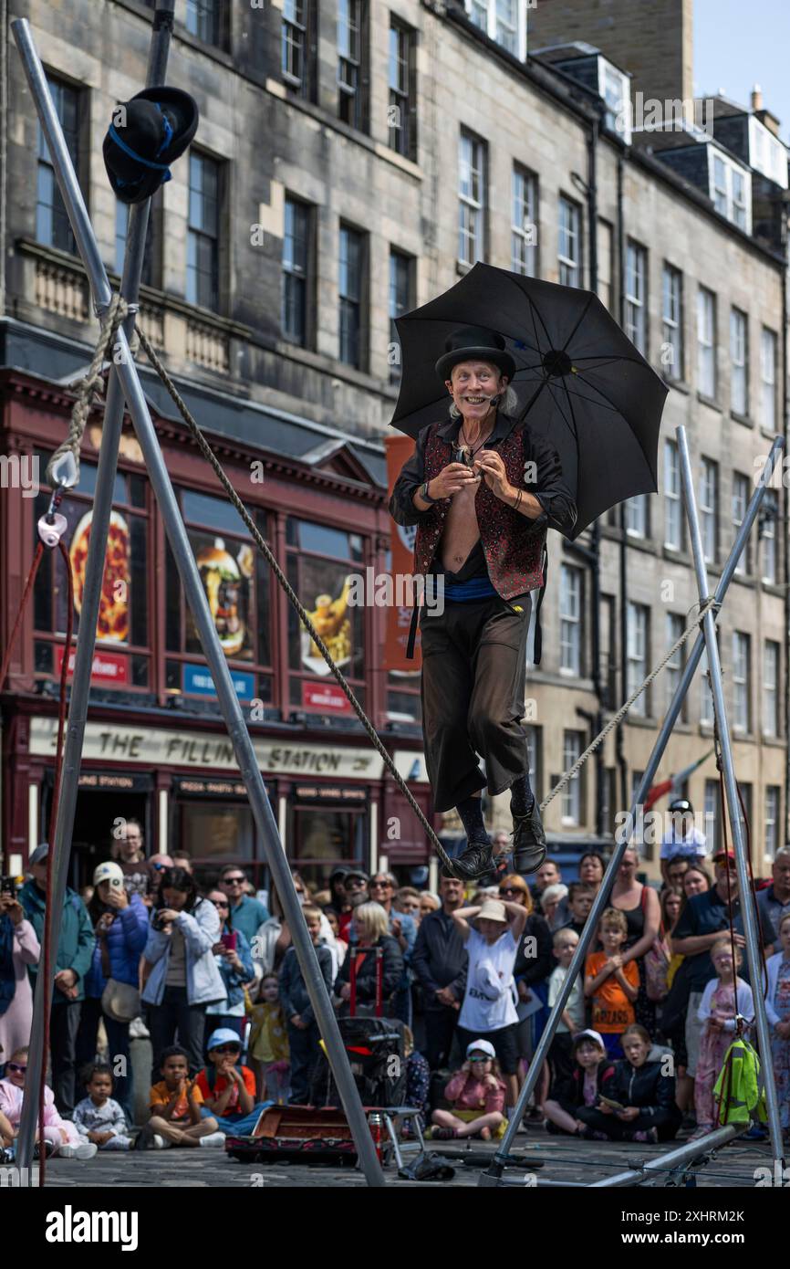 Street performers and spectators at a high-wire acrobatics performance ...