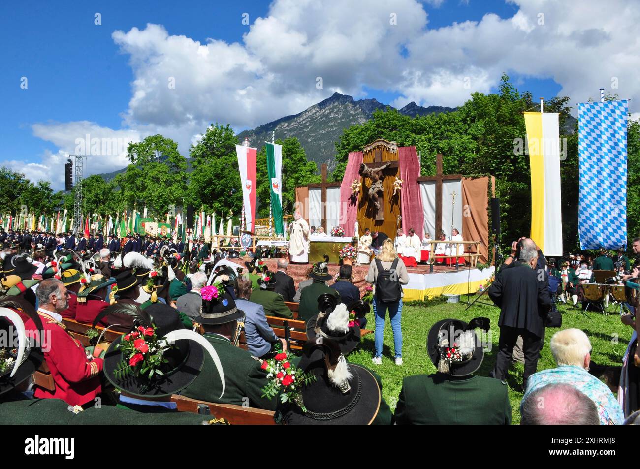 Gathering of people in traditional dress with colourful flags in front ...