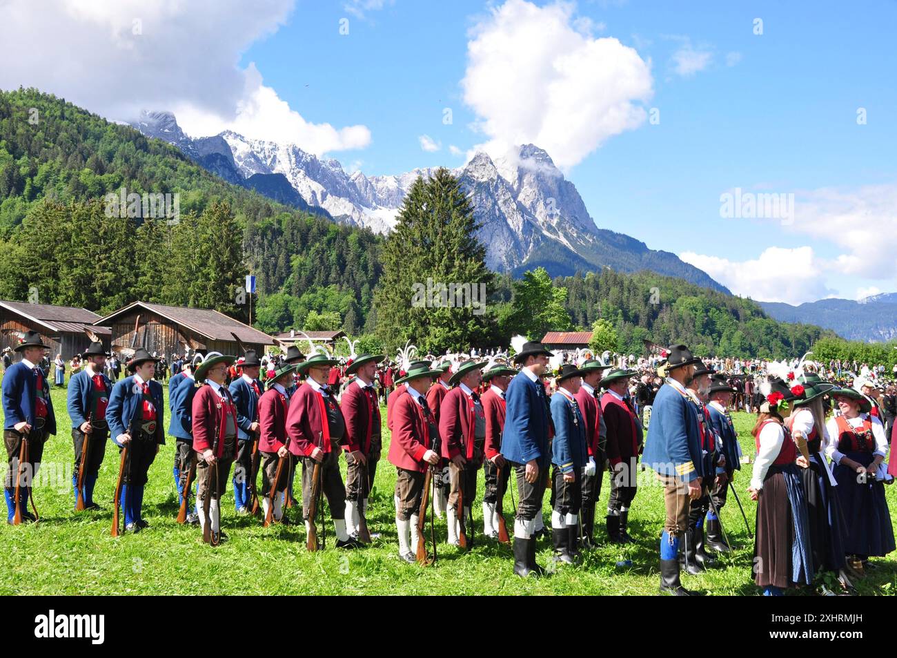 Men in traditional costumes standing on a green meadow with Alps in the ...