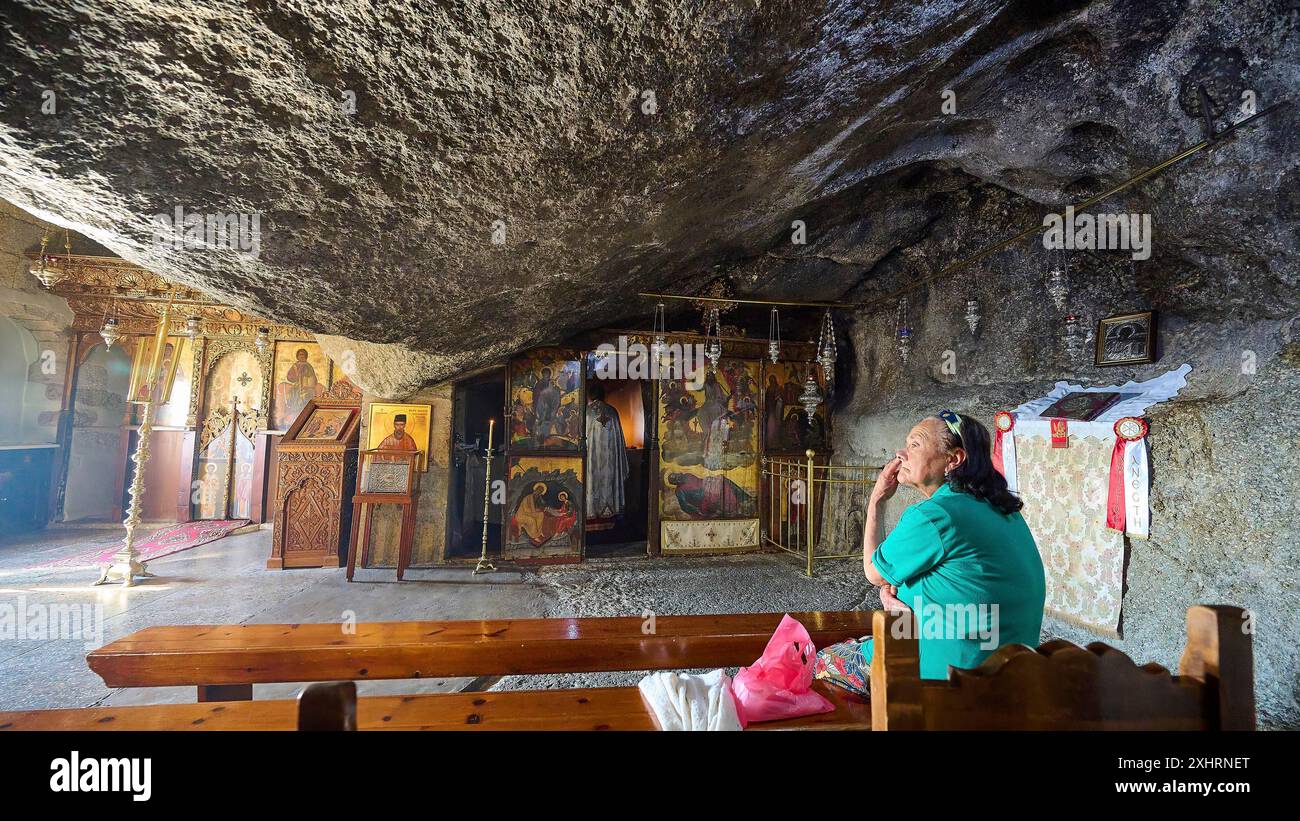 Interior view of a church with a woman praying on a wooden bench and ...