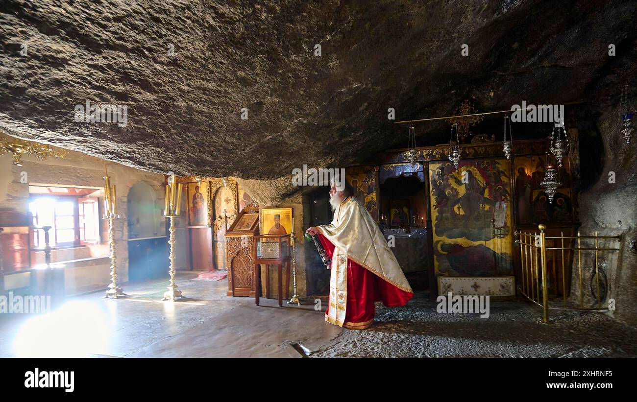 Priest in a sacred space carved into the rock in front of a decorated ...