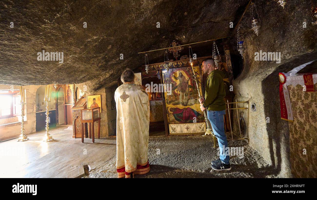 Religious ceremony in a rock cave with a priest and a man in front of ...