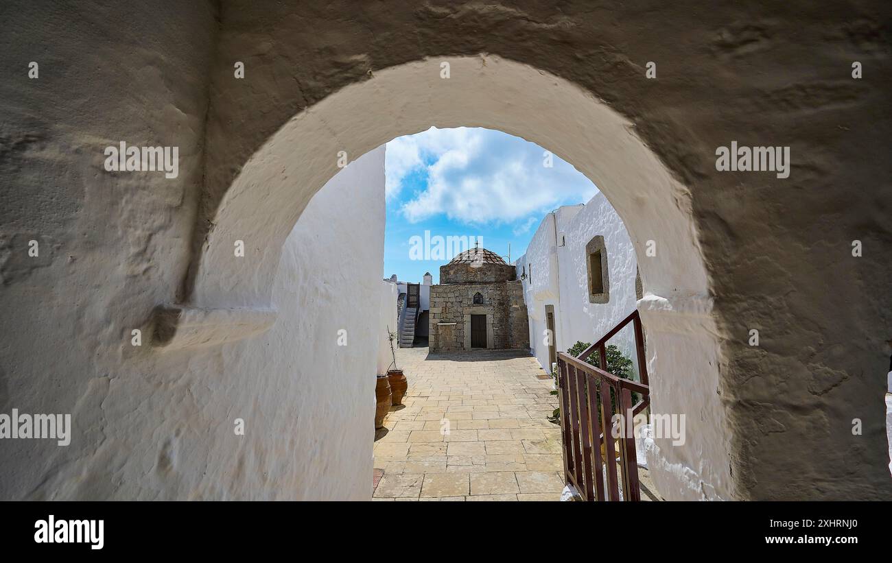 Passage through a stone arch with a view of white buildings and blue ...