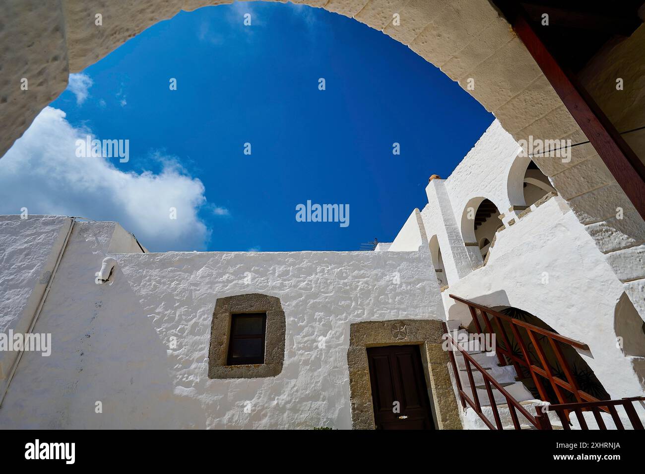 View from below of white buildings and a staircase under an arch in the ...
