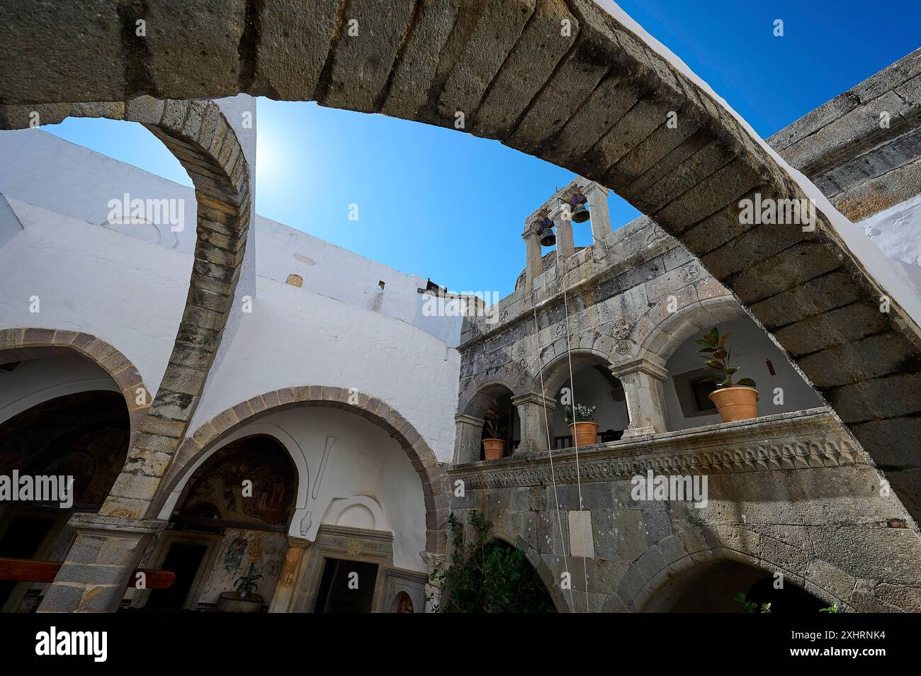 Historic monastery courtyard with stone arches, a tower and hanging ...