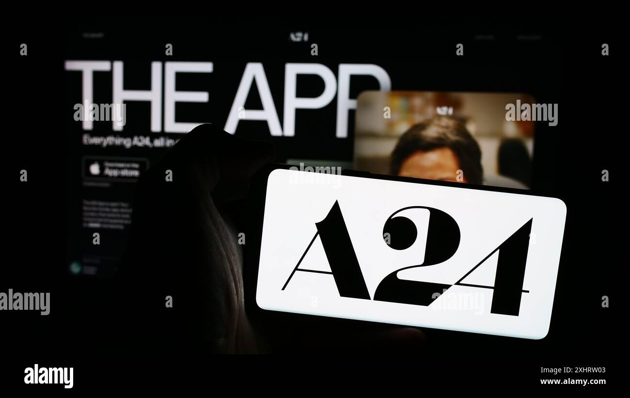 Person holding mobile phone with logo of American entertainment company A24 Films LLC in front ...