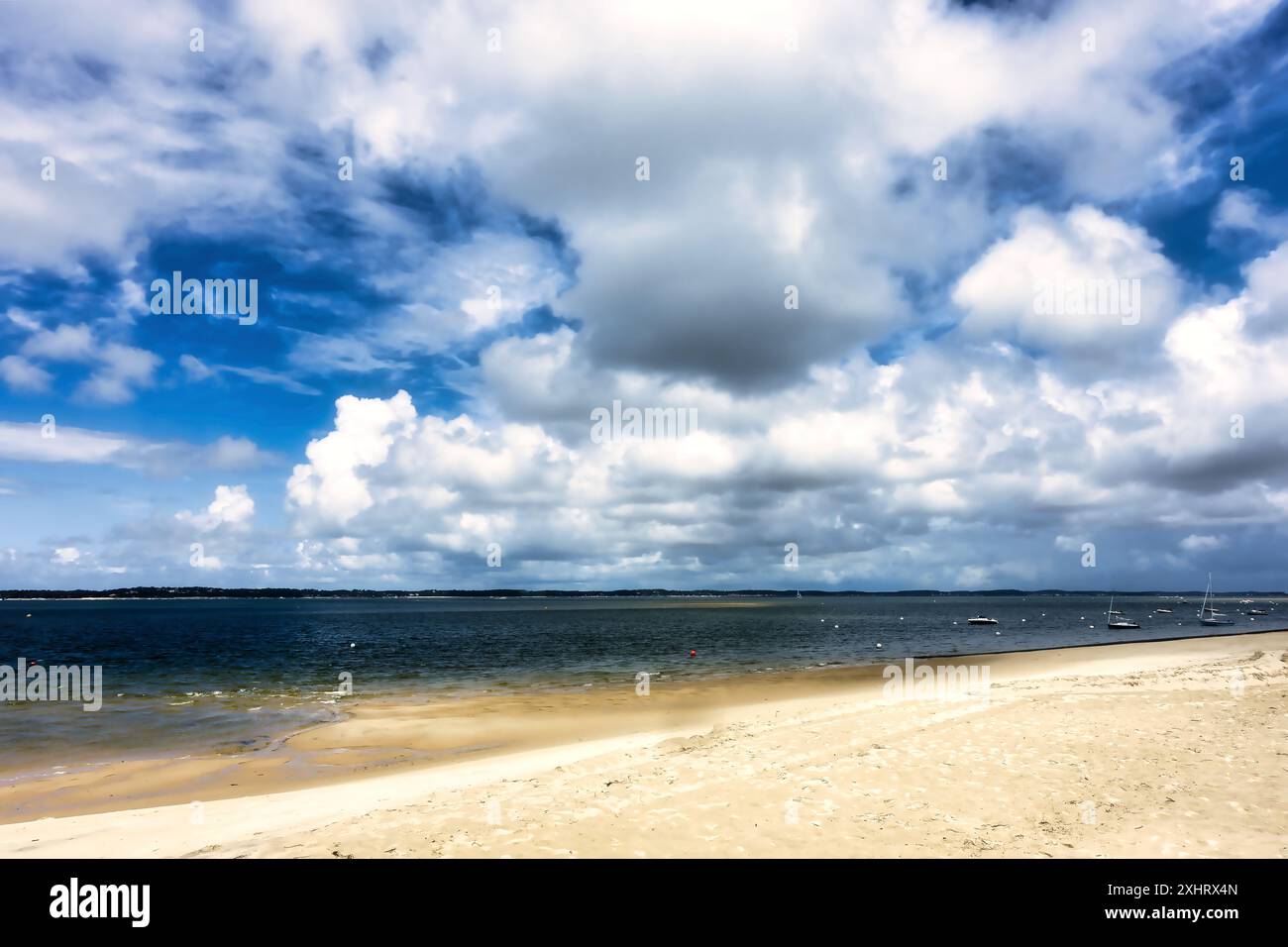 Shot of a wide beach with clouds reflecting in the water and blue sky ...