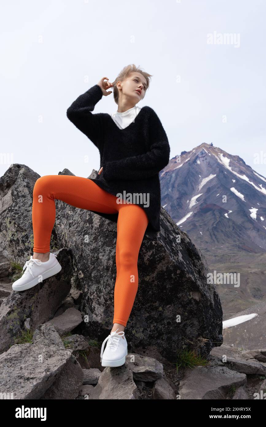 Authentic Caucasian Ethnicity Woman is sitting on rock in mountains ...