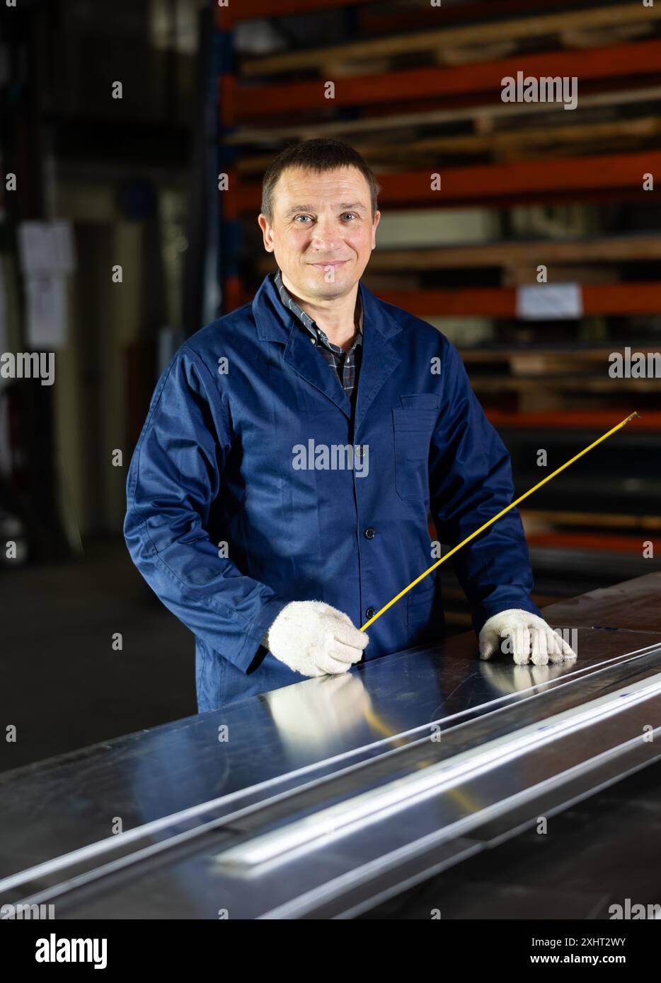 Positive worker marking metal sheet with tape measure in workshop Stock ...