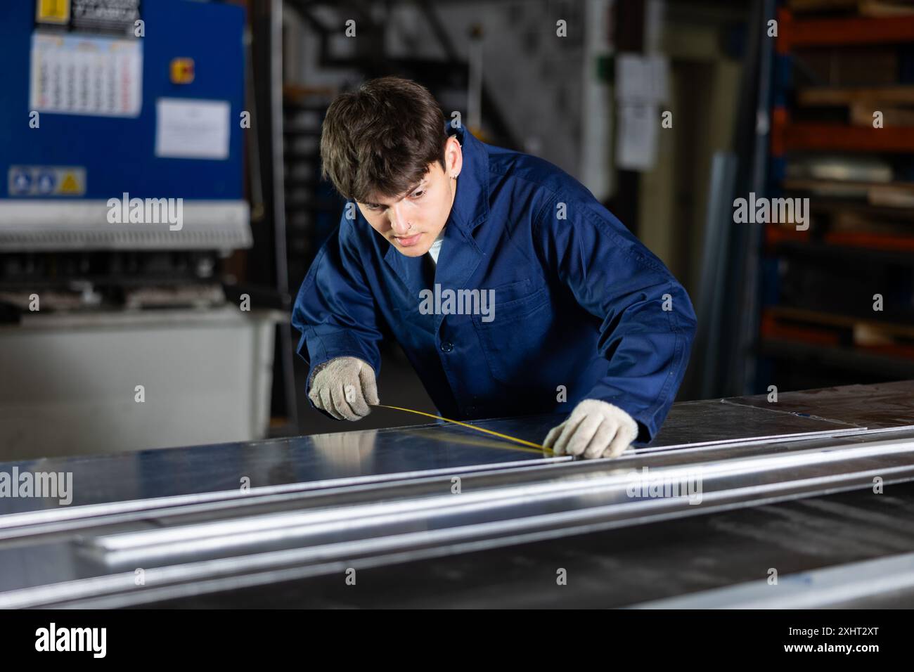 Guy measuring sheet of metal with tape measure Stock Photo - Alamy
