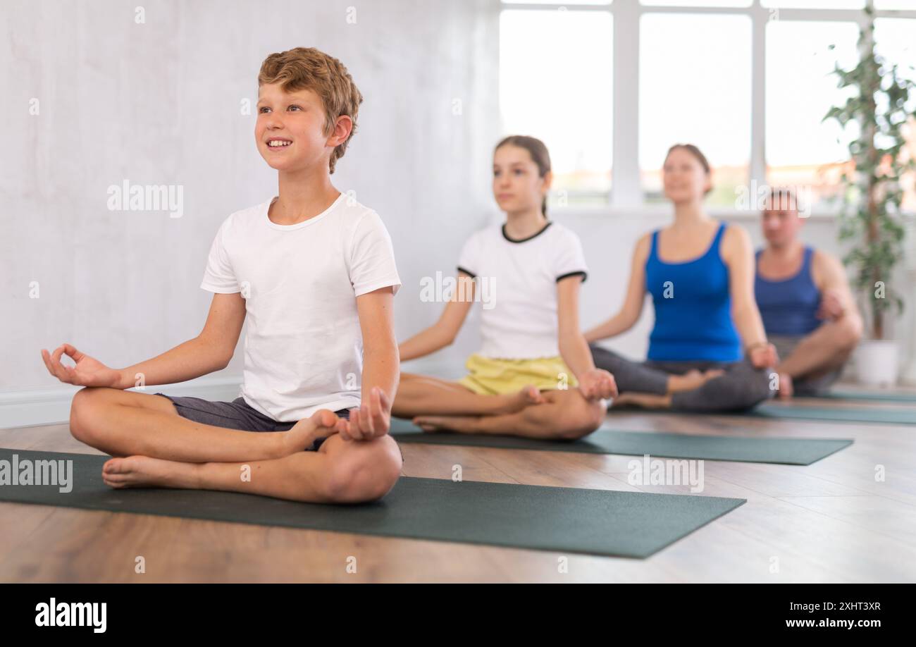 Happy preteen boy practicing lotus pose of yoga with his family Stock ...