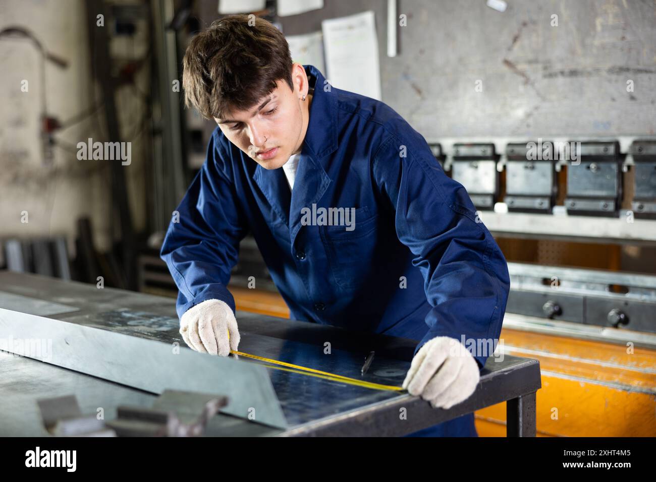 Guy measuring sheet of metal with tape measure Stock Photo - Alamy