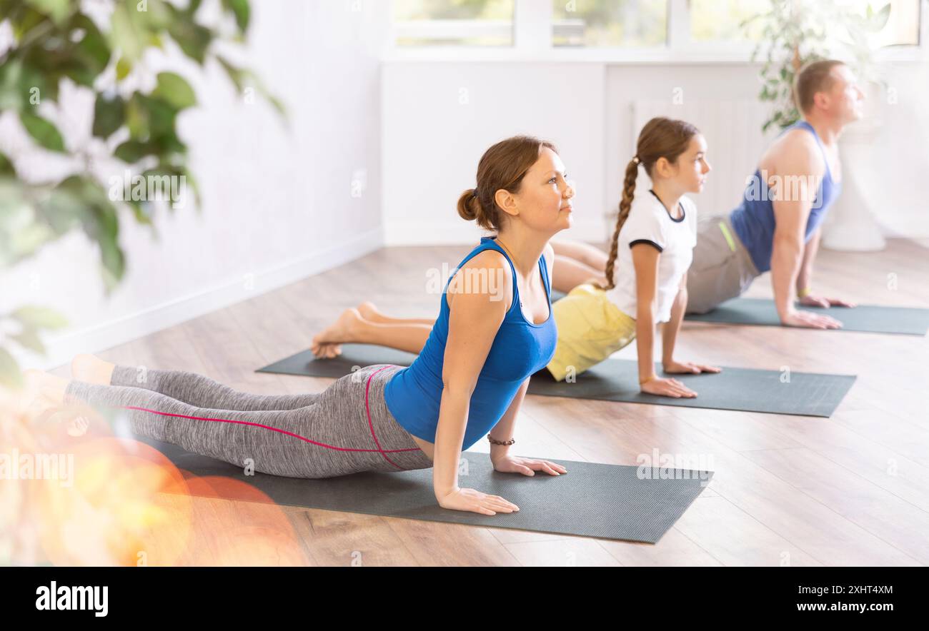 School children and their parents exercising on mats in Cobra position ...