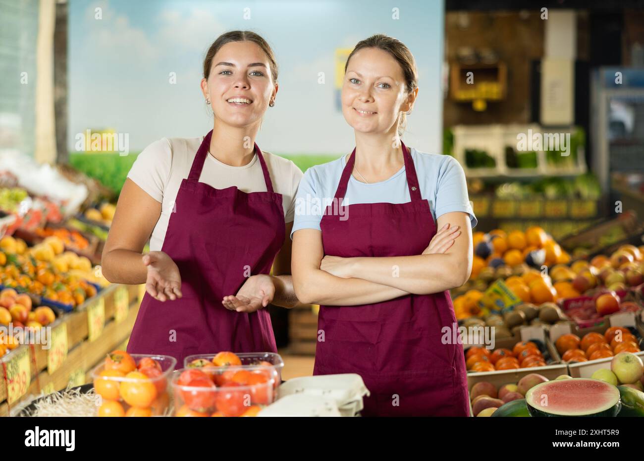 Happy two female sellers wearing apron and standing next to organic ...
