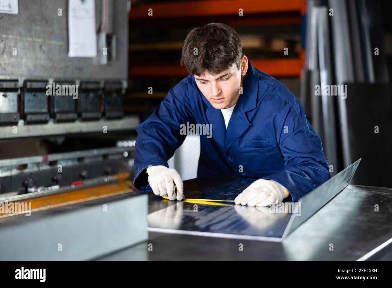 Guy measuring sheet of metal with tape measure Stock Photo - Alamy