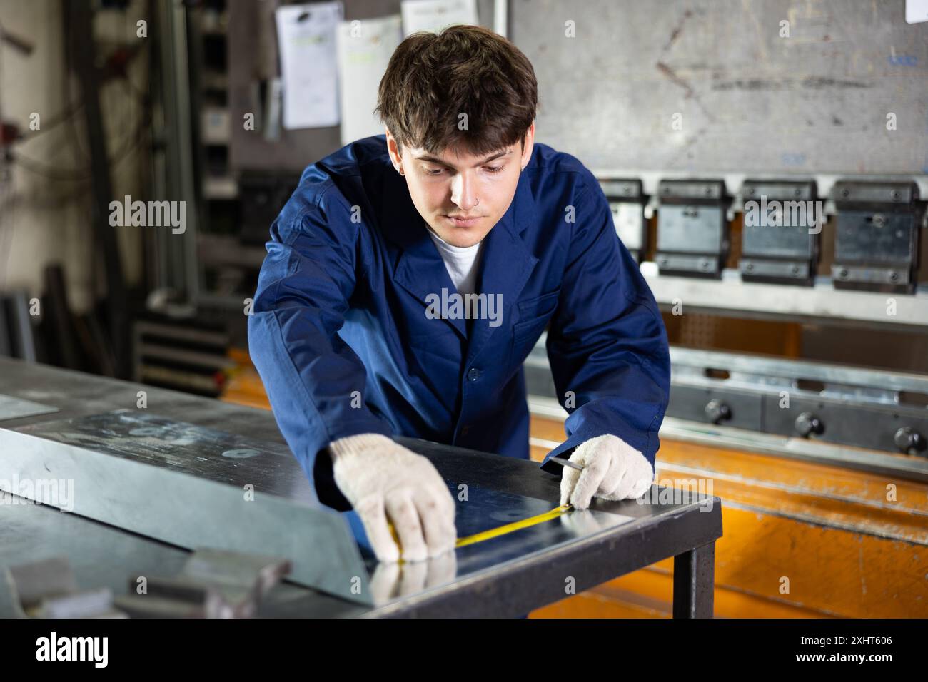 Guy measuring sheet of metal with tape measure Stock Photo - Alamy