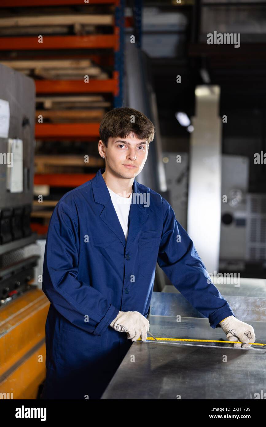 Guy measuring sheet of metal with tape measure Stock Photo - Alamy