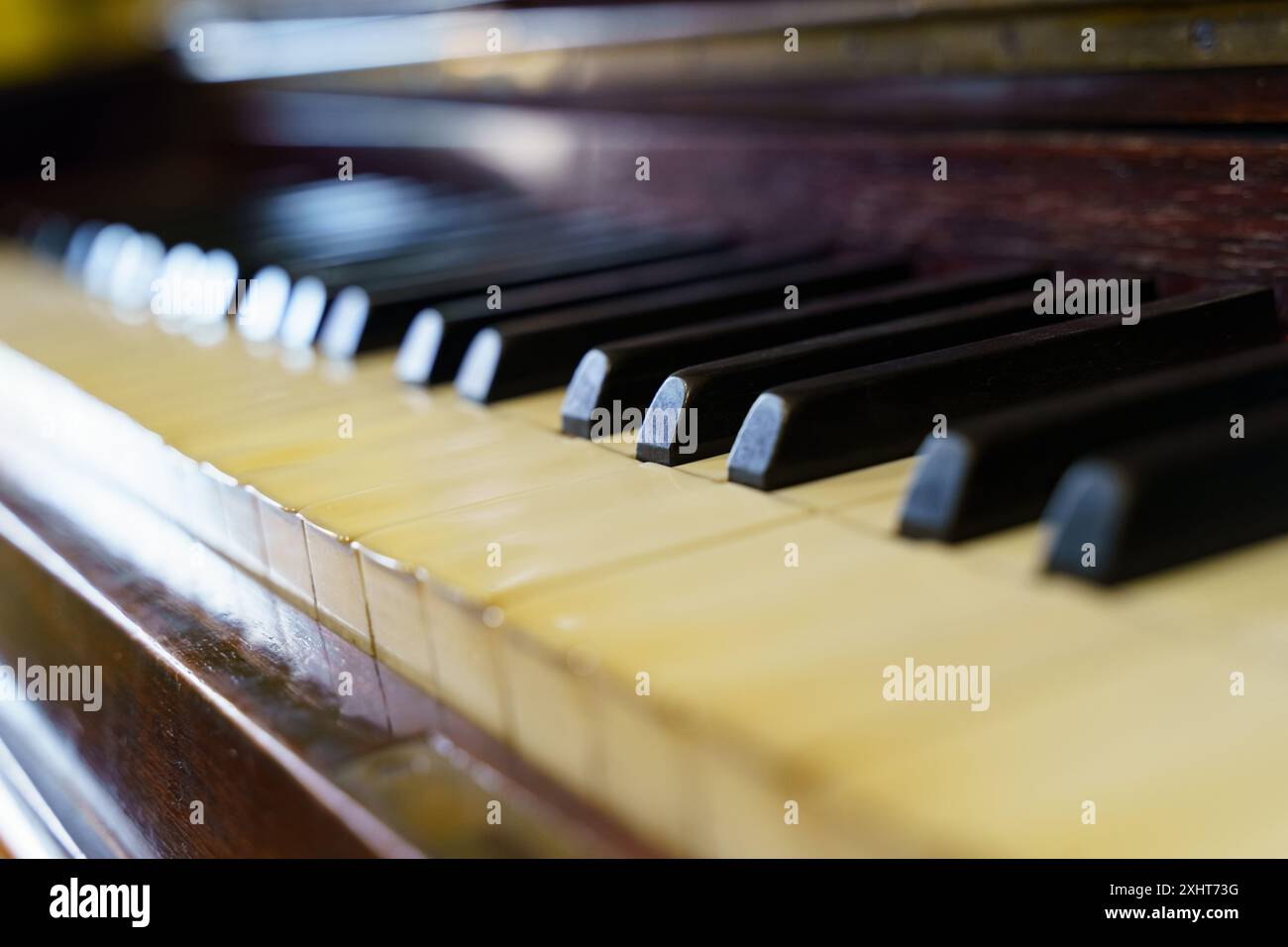 A close-up of a piano's keyboard, revealing the worn keys and the ...