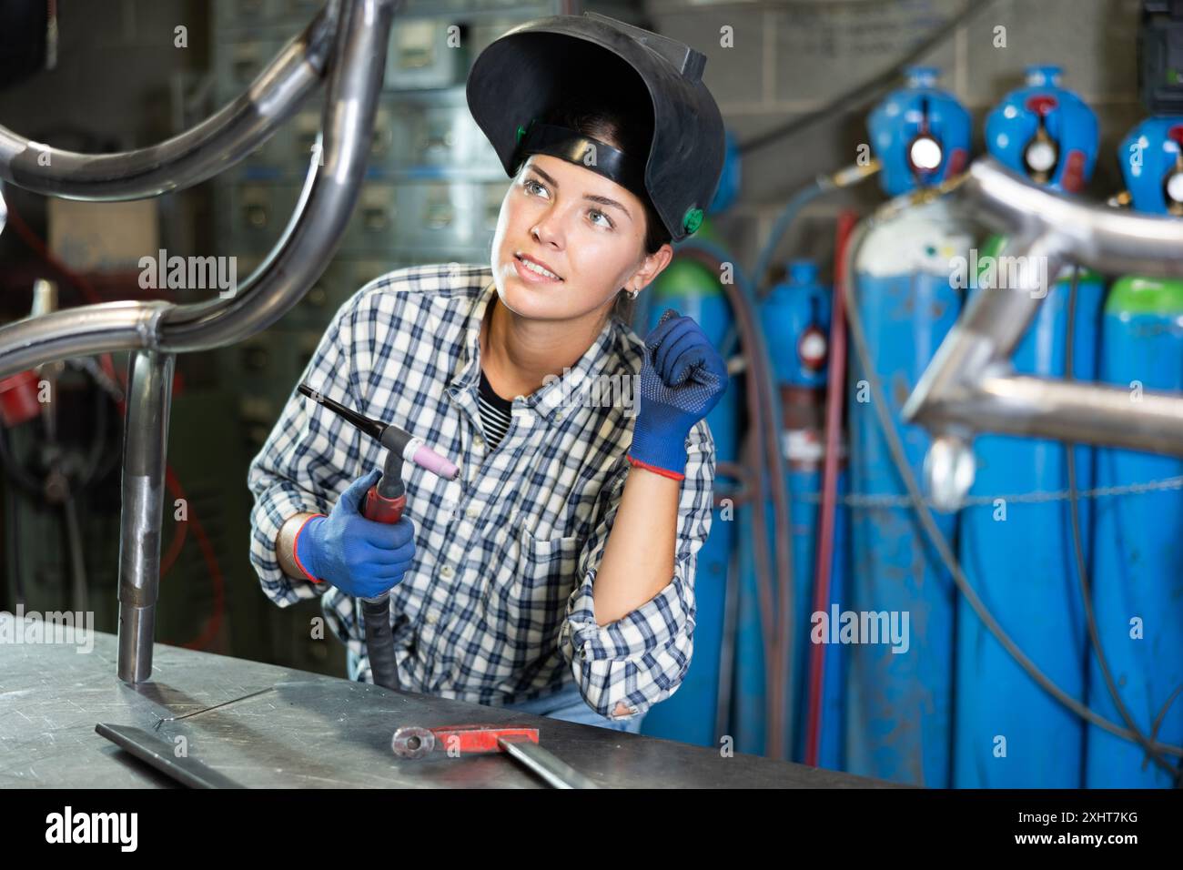 Female welder welding metal pipe structure in workshop Stock Photo - Alamy