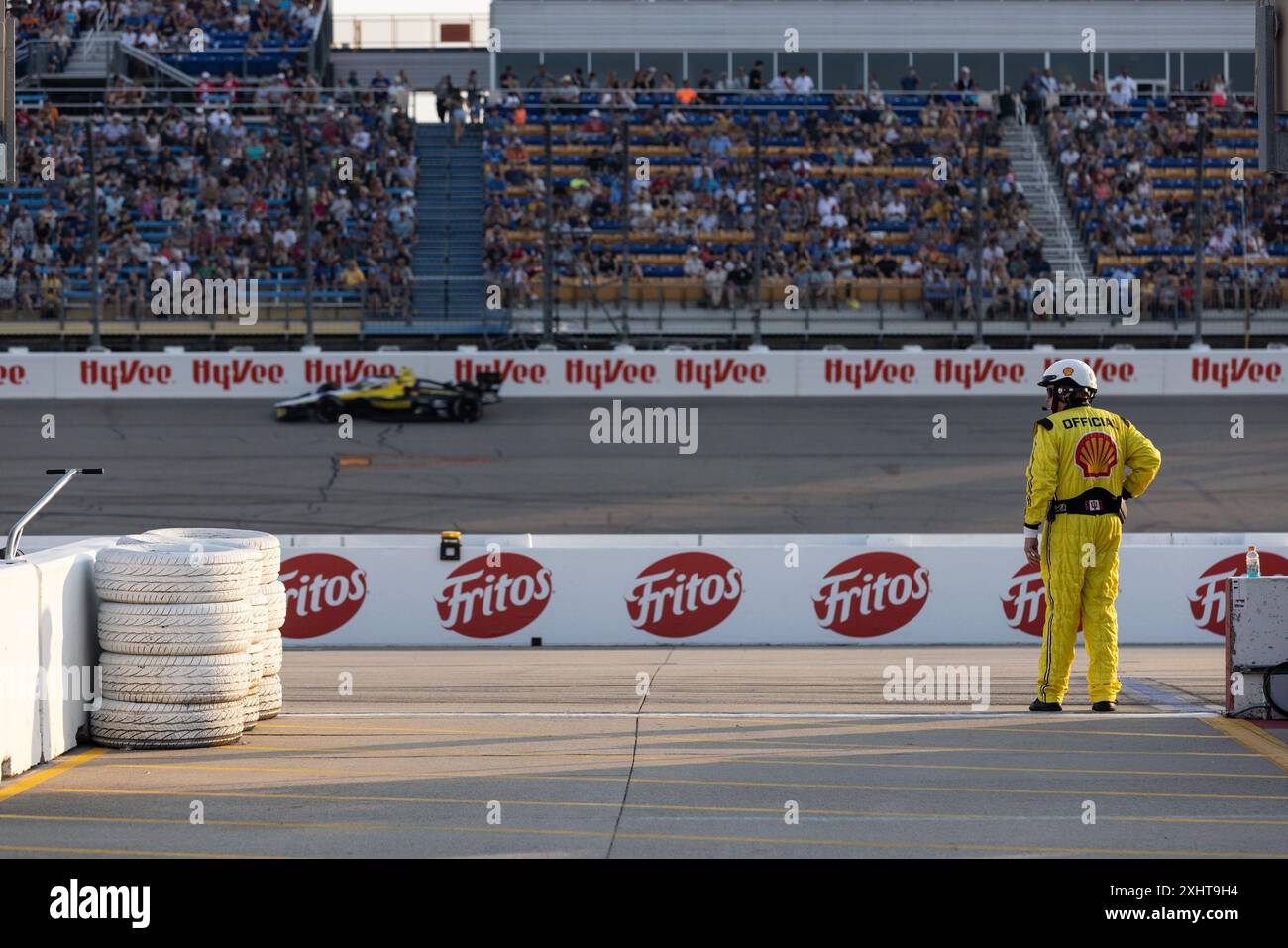Cars circle the track during the race as a race official looks on. The ...