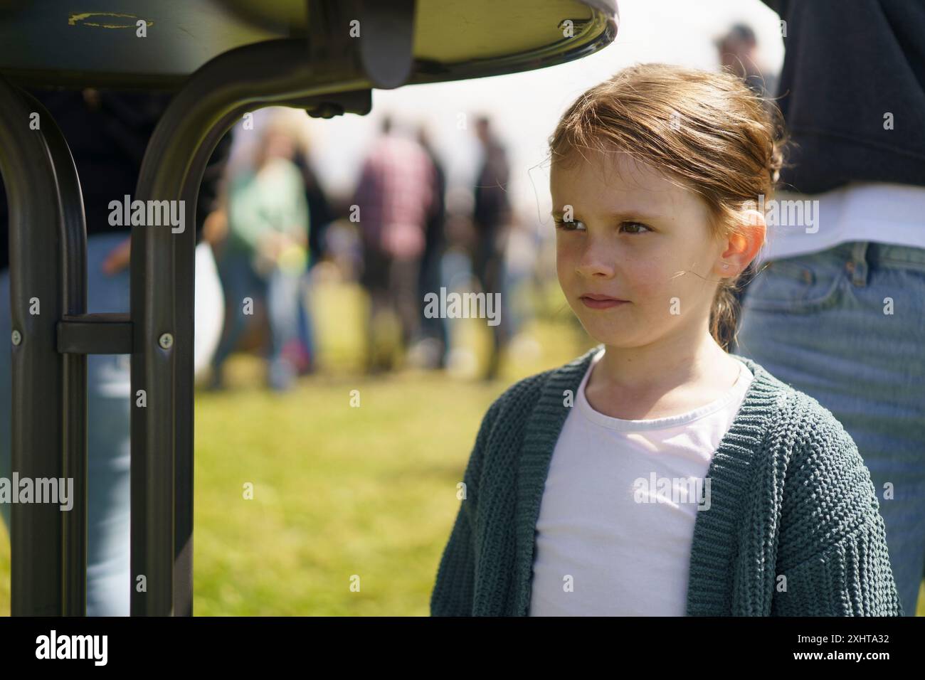 A cute beautiful little toothless red-haired girl in a jacket stands ...
