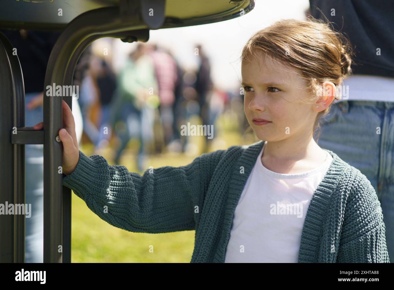A cute beautiful little toothless red-haired girl in a jacket stands ...
