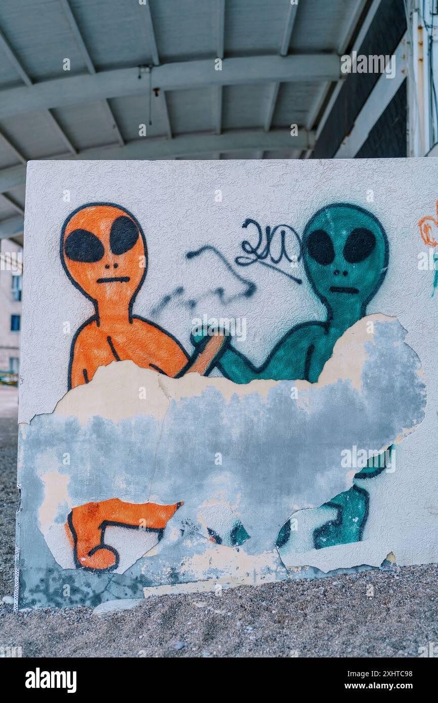 Scraped graffiti on a concrete wall depicting aliens shaking hands ...