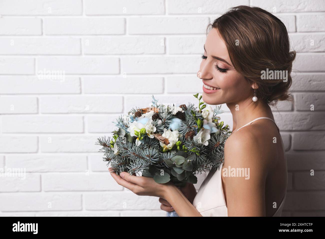 Beautiful bride with winter wedding bouquet near white brick wall Stock ...