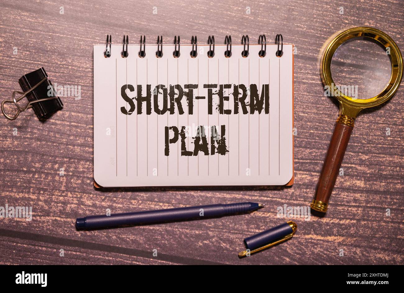 Notebook with text SHORT-TERM PLAN on a table with charts,pen and ...