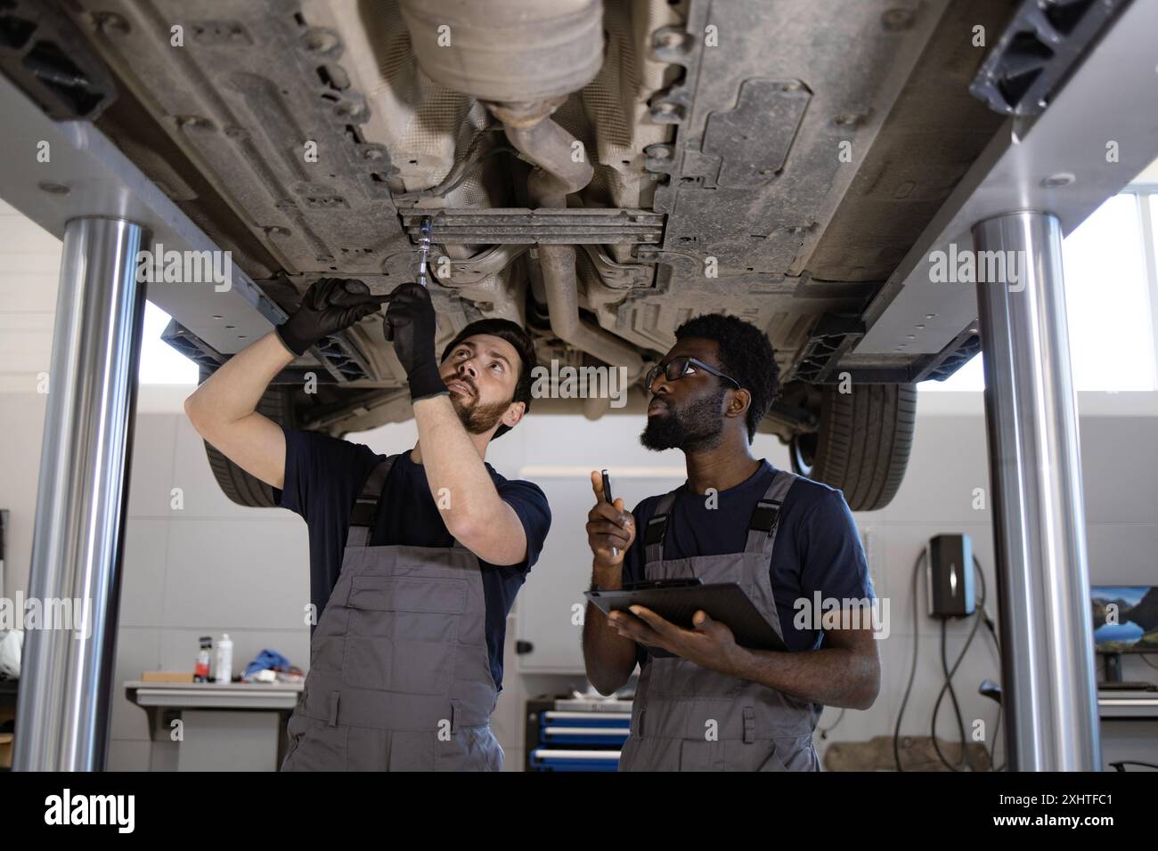 Two mechanics inspecting vehicle in professional auto repair shop Stock Photo - Alamy