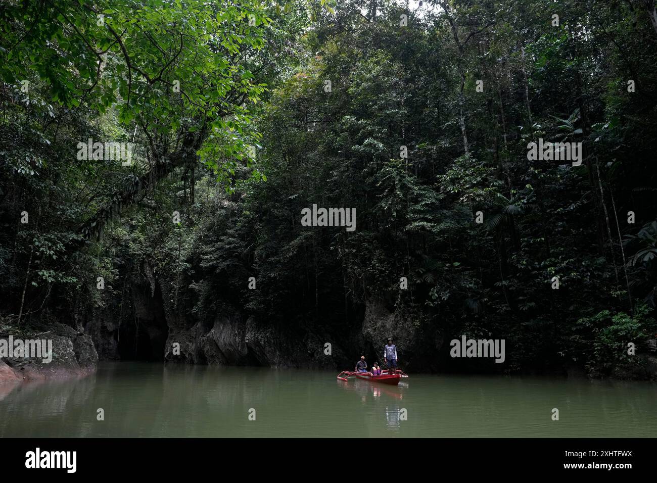 Men on a boat maneuver near the Bokimaruru Cave in Central Halmahera ...
