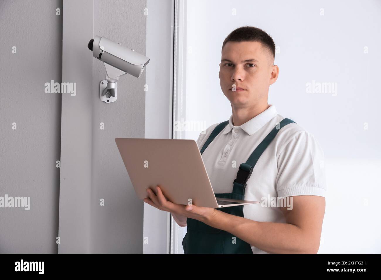 Technician with laptop installing CCTV camera indoors Stock Photo - Alamy