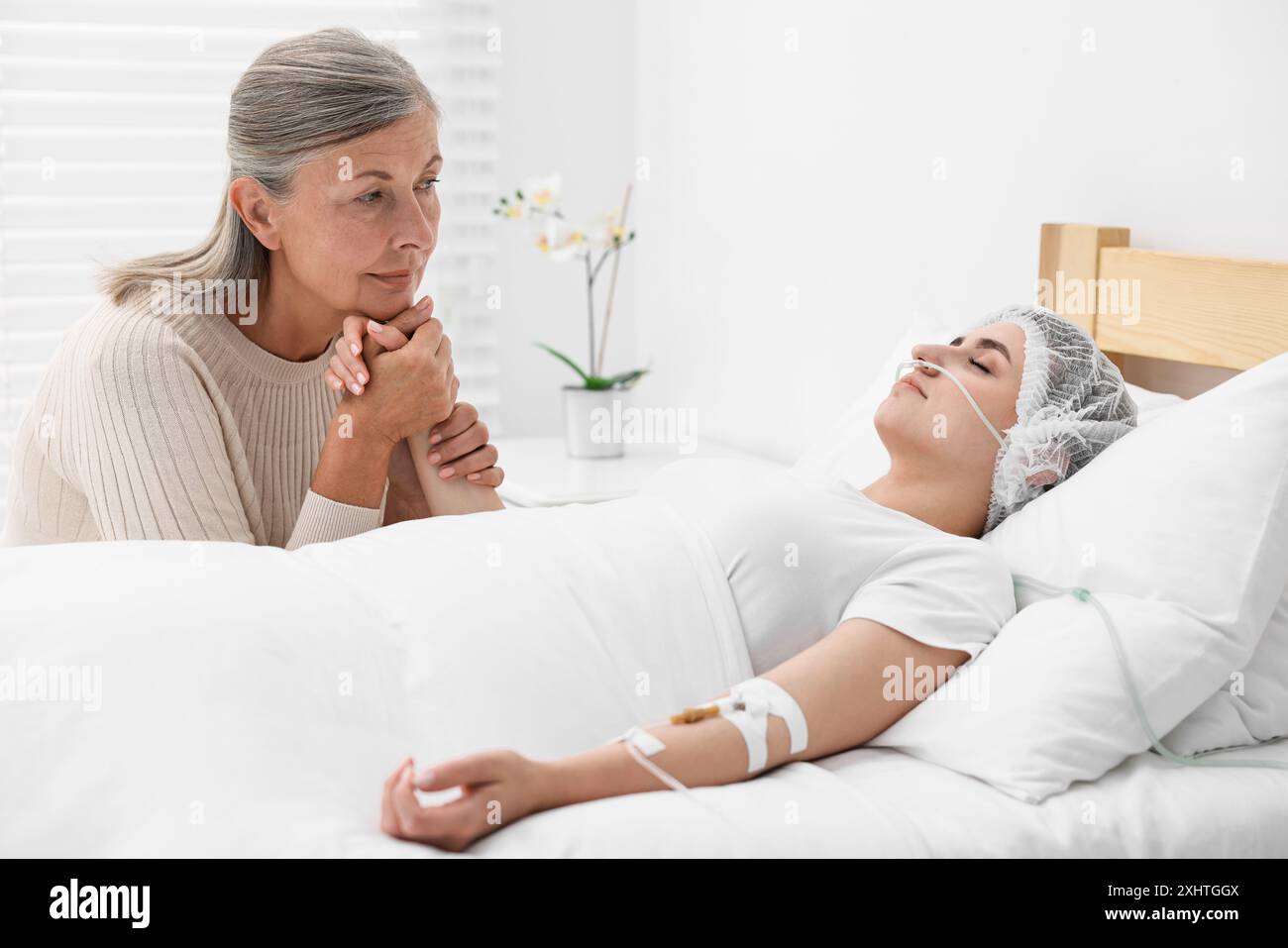 Coma patient. Sad mature woman near her unconscious daughter in ...