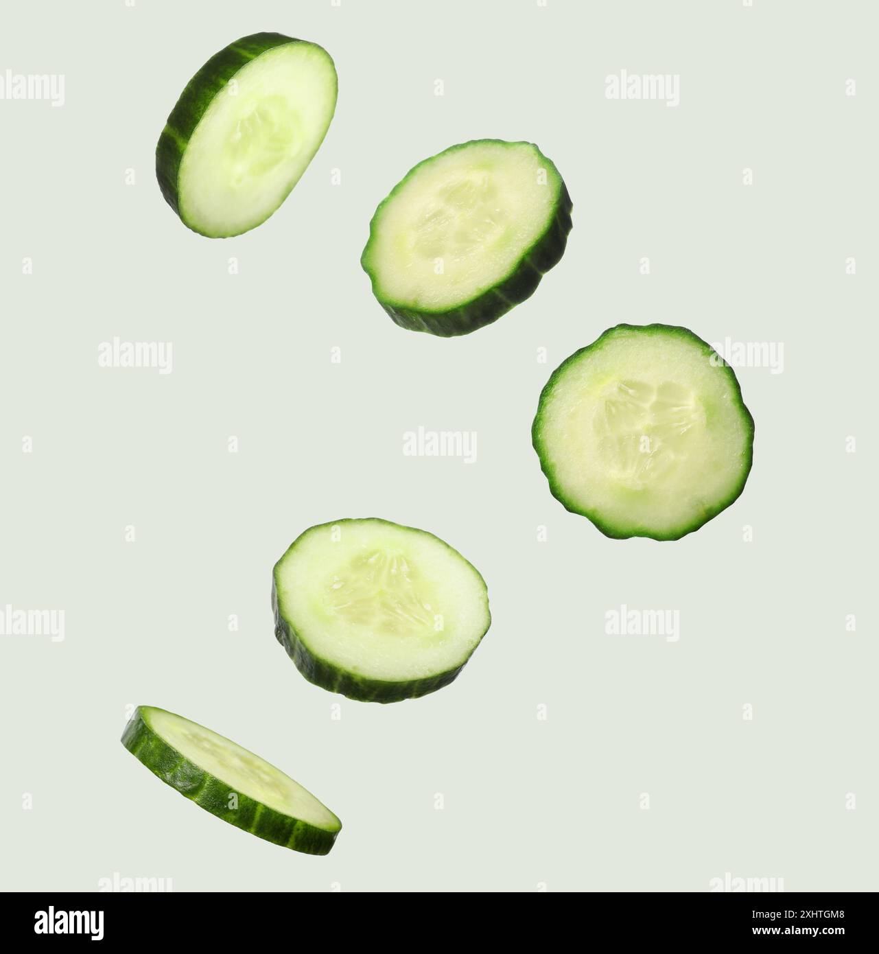 Fresh cucumber slices in air on light grey background Stock Photo - Alamy