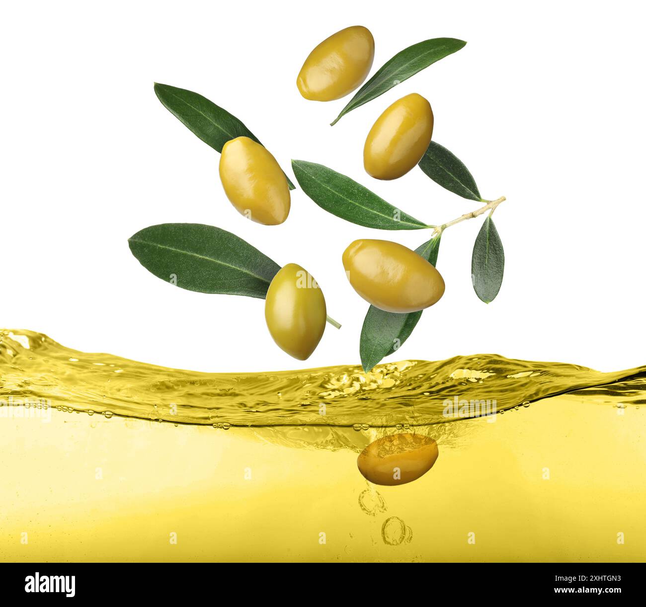 Green olives and leaves falling into cooking oil on white background ...