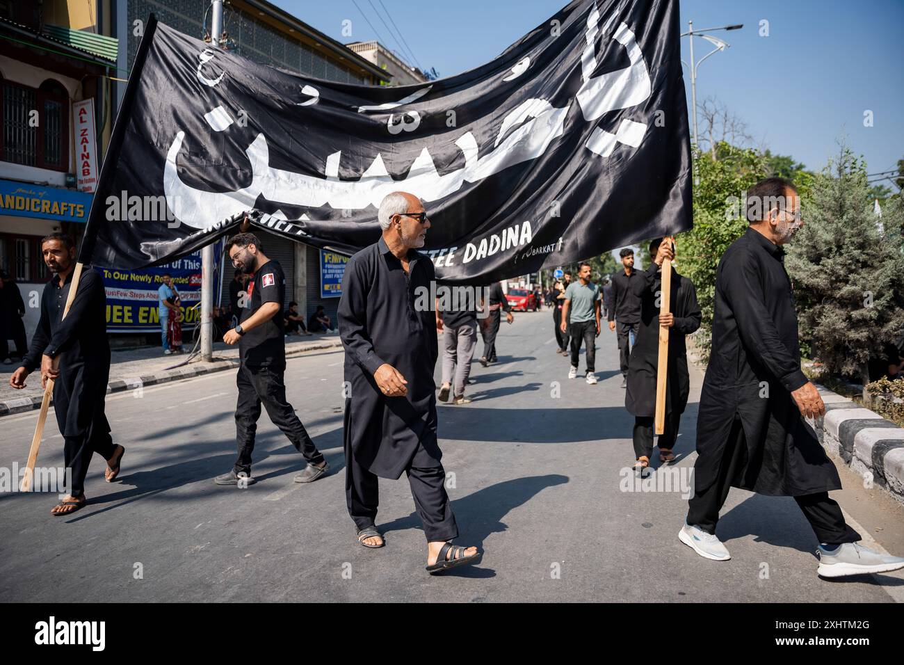 Kashmiri Shia Muslims carry a religious banner that says ''Ya Hussain" as they walk in a ...
