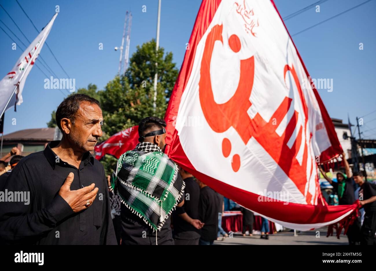 A Kashmiri Shia Muslim mourner beats his chest as he passes by a religious banner that says ''Ya ...