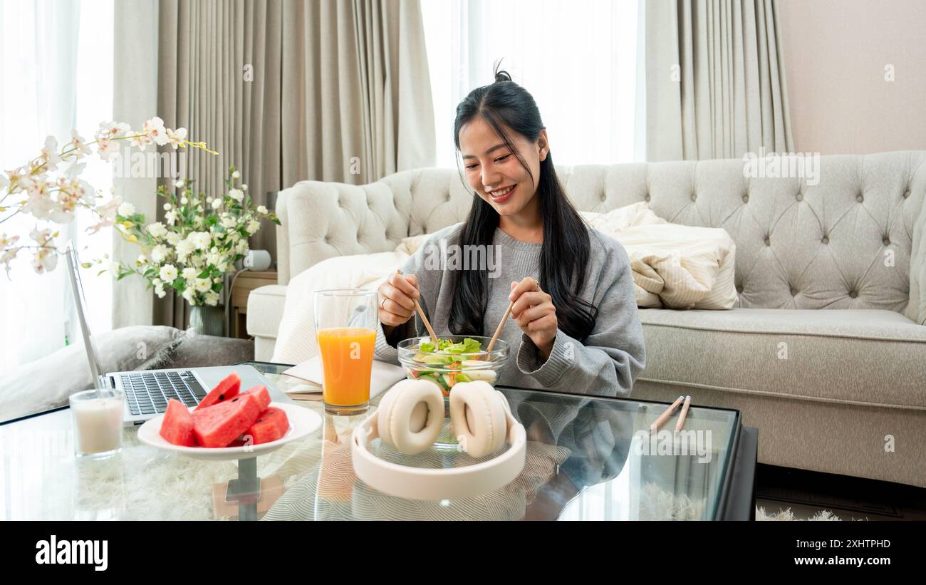 A positive, charming young Asian woman having breakfast, eating healthy ...