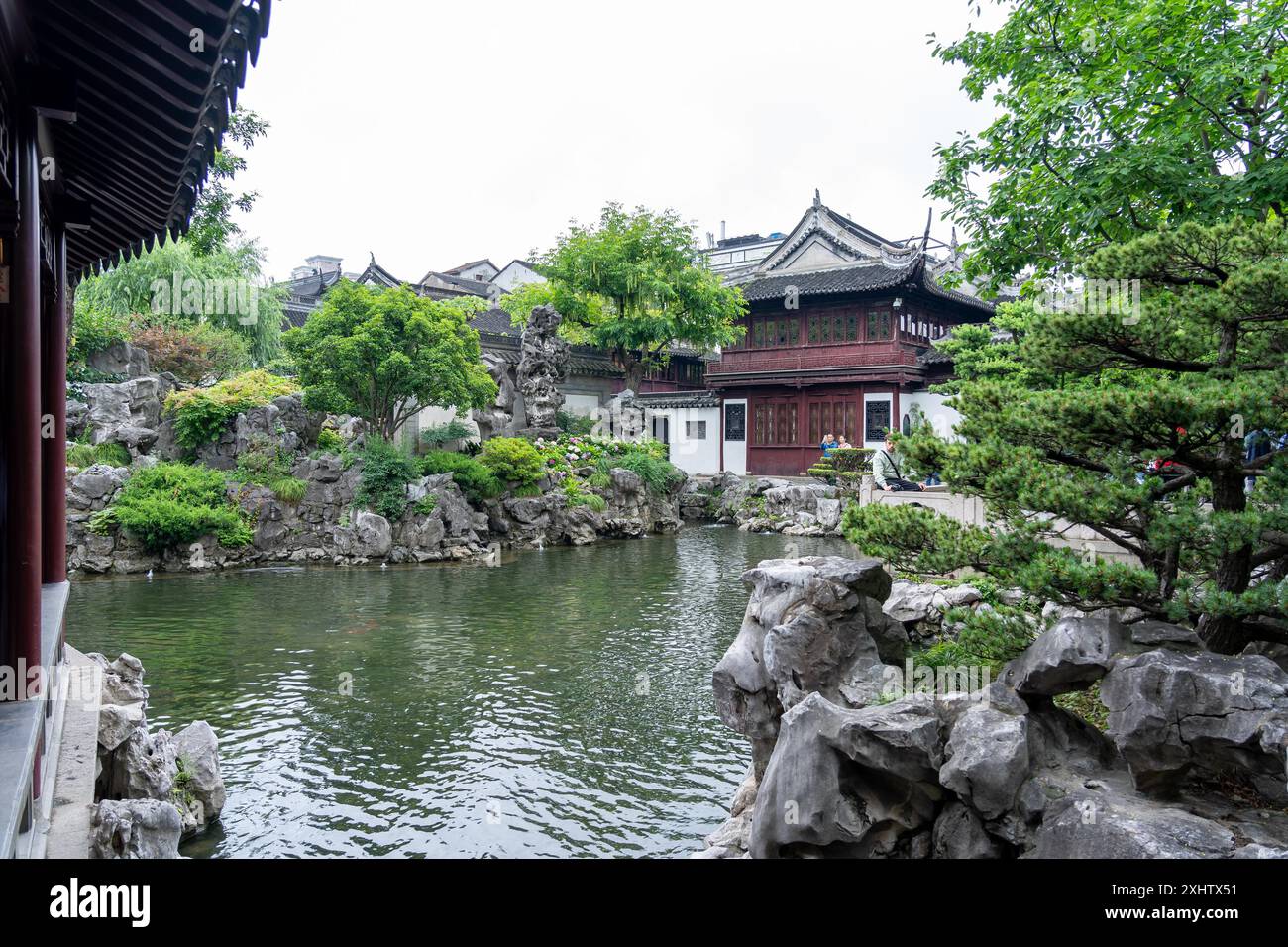 Shanghai, China - June 06, 2024 : A peaceful pond with a traditional ...