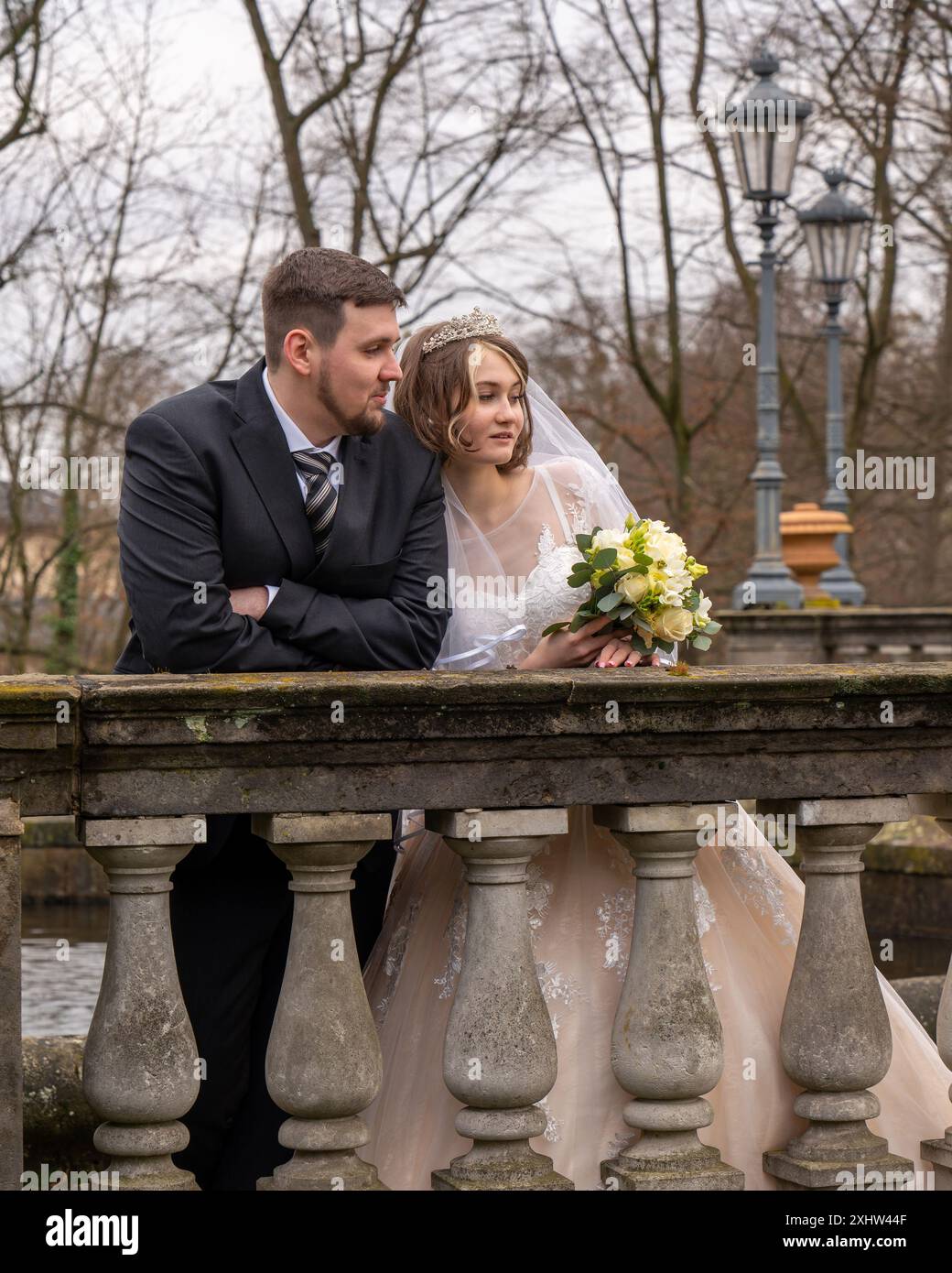 Front view of a joyful bride and groom, a girl with a bouquet of white ...